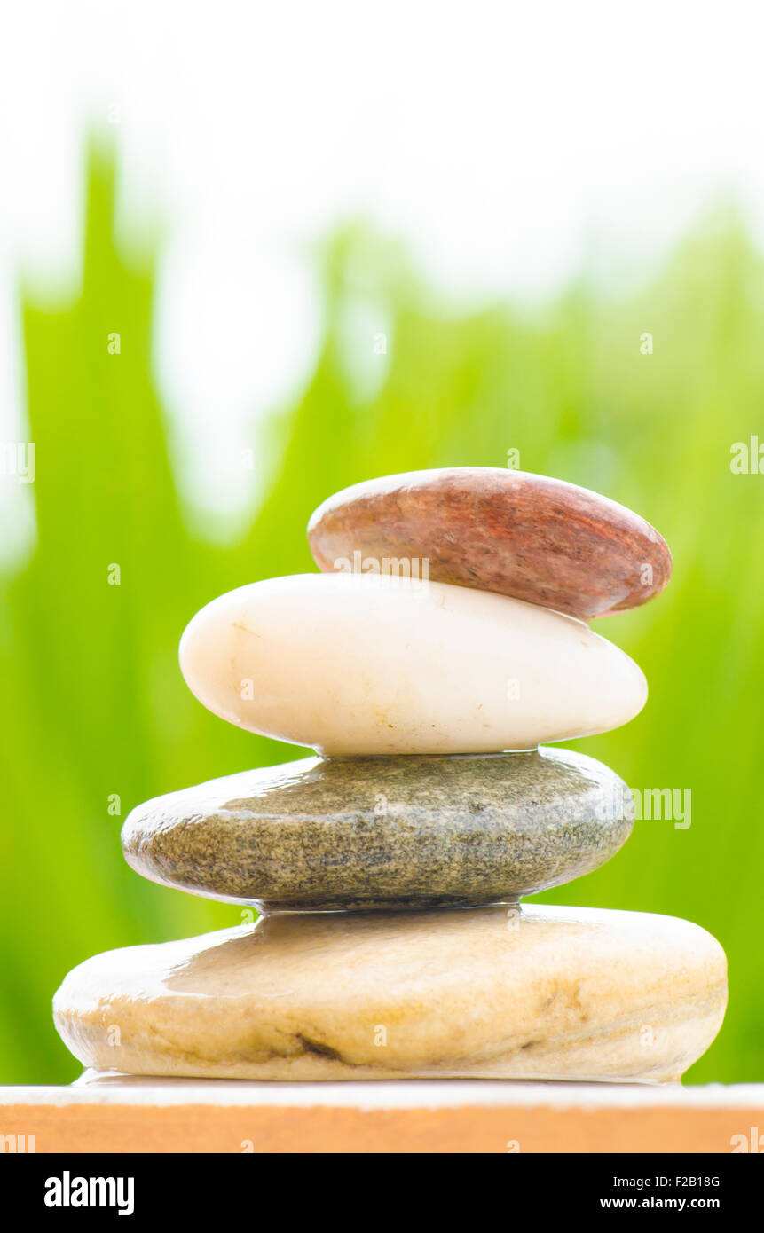 Stack of 4 rocks pyramid of different colors on green grass background ...