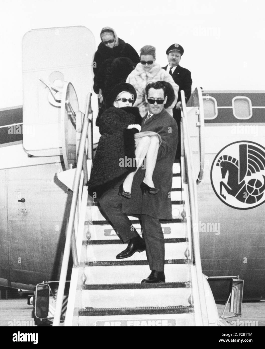 Barbara Hutton is carried off an Air France by her companion, Colin ...