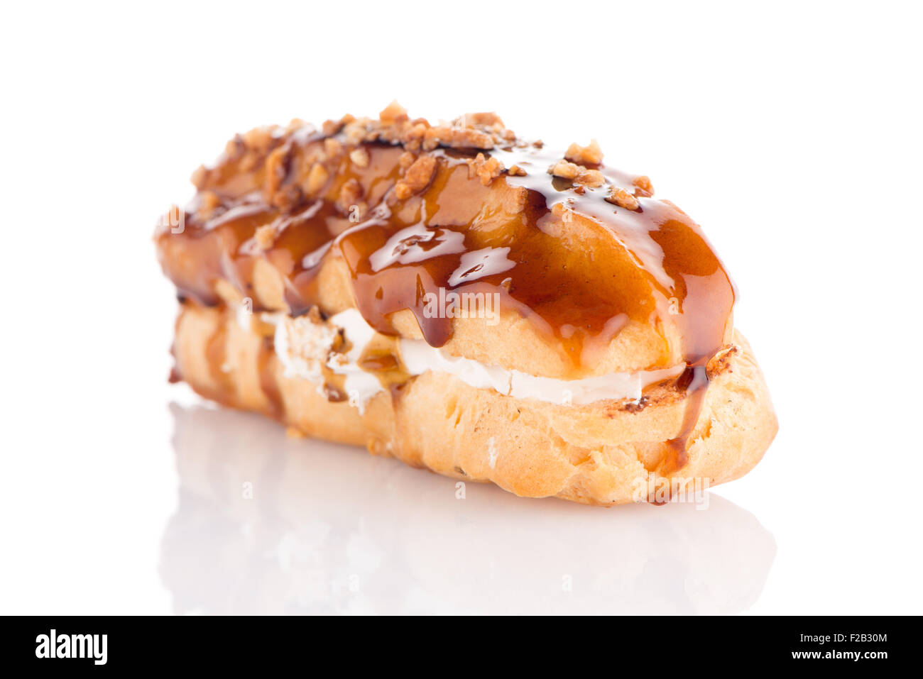 Eclair with caramel decoration on white reflective background Stock ...
