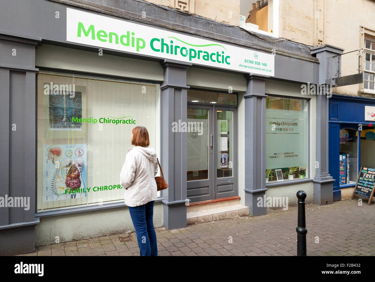 A woman looking in the window of a Chiroprac Surgery, or Chiropracter ...