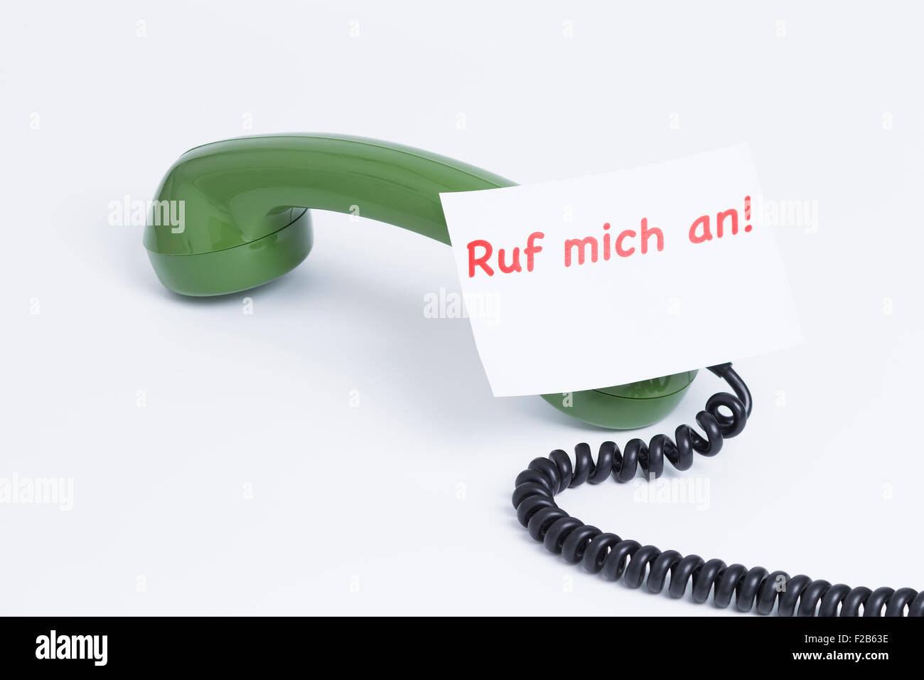 Image shows a telephone earphone with note "ruf mich an Stock Photo - Alamy