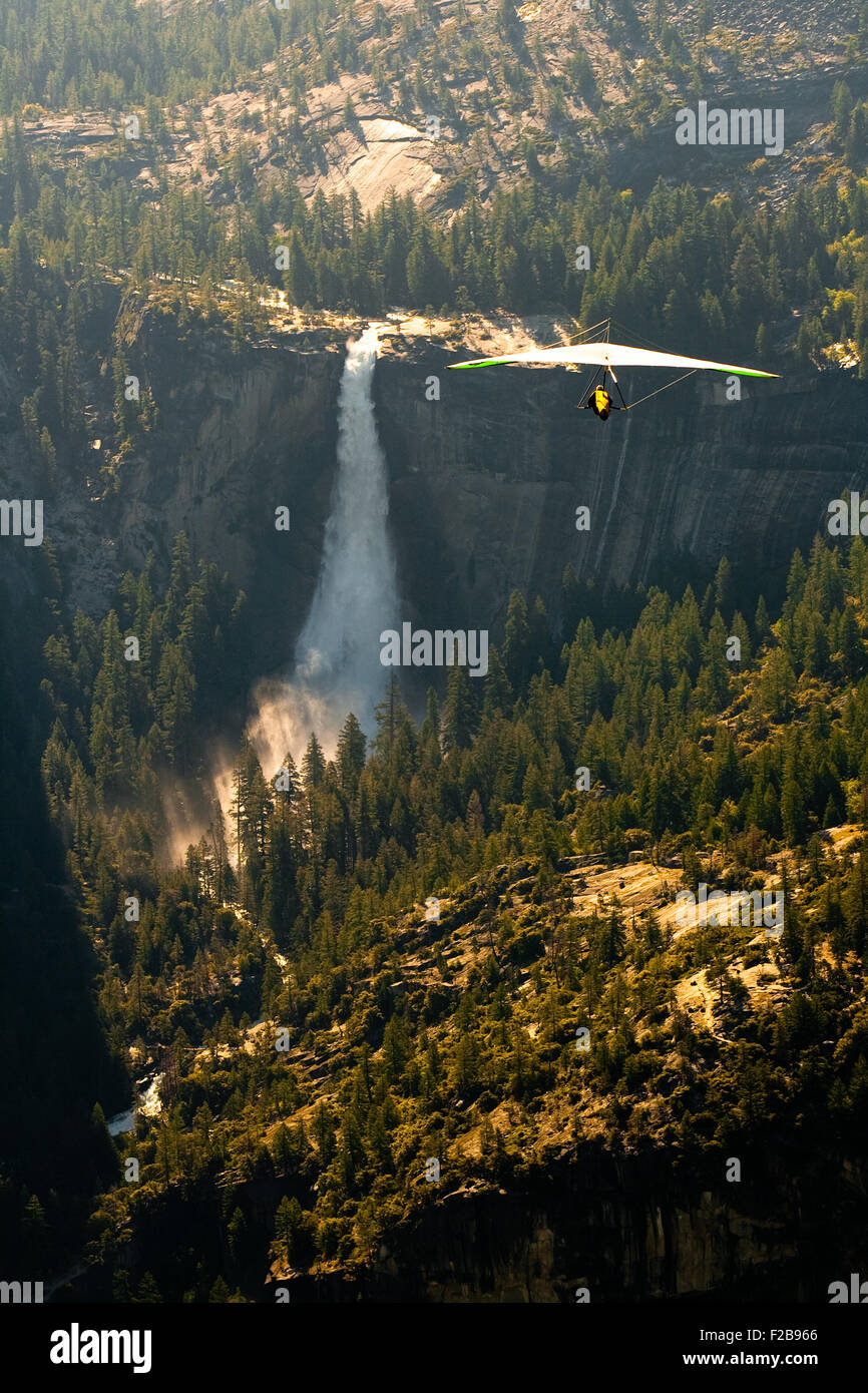 Hang glider soars high over waterfall and forest in Yosemite National ...