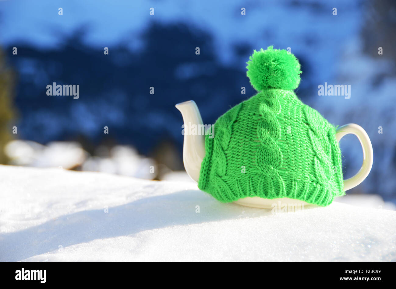 Tea pot in the knitted cap on the snow Stock Photo - Alamy