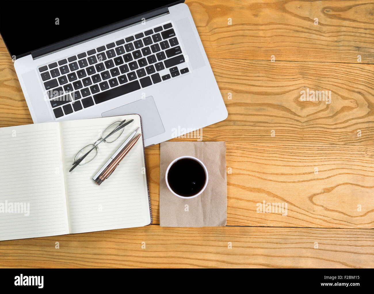 Top view of computer laptop with dark coffee, notepad, reading glasses ...