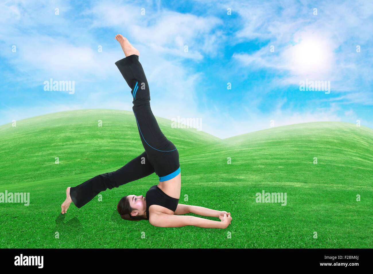 Young woman doing yoga exercise on grass with sky Stock Photo - Alamy
