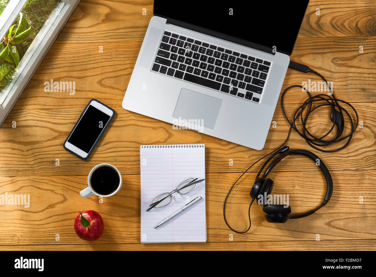 Working desktop consisting of laptop, headphone set, notepad, pen ...