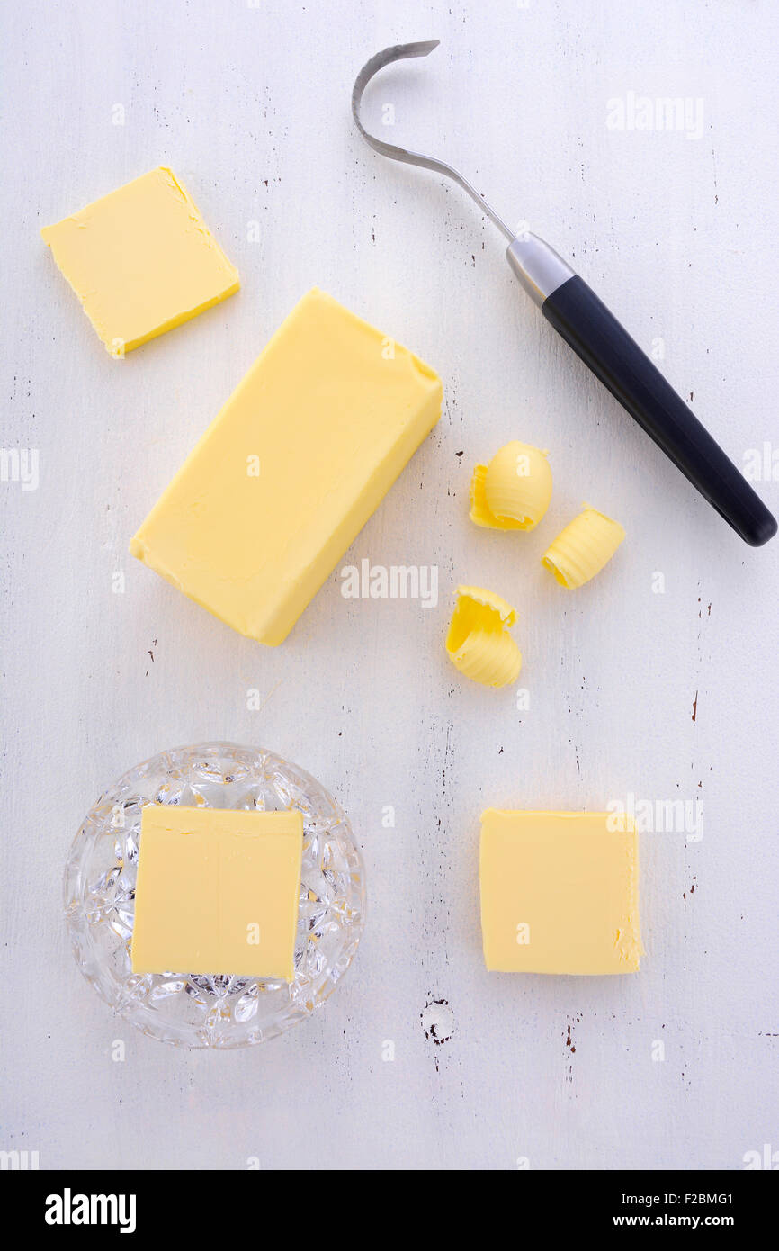 Butter on white wood table with slices, block, crystal butter dish and ...