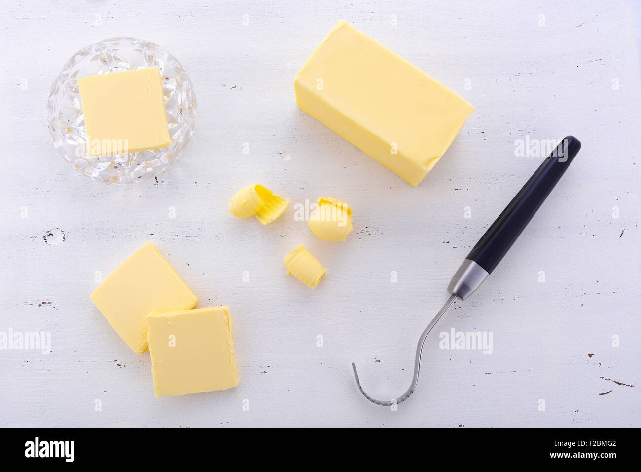 Butter on white wood table with slices, block, crystal butter dish and ...