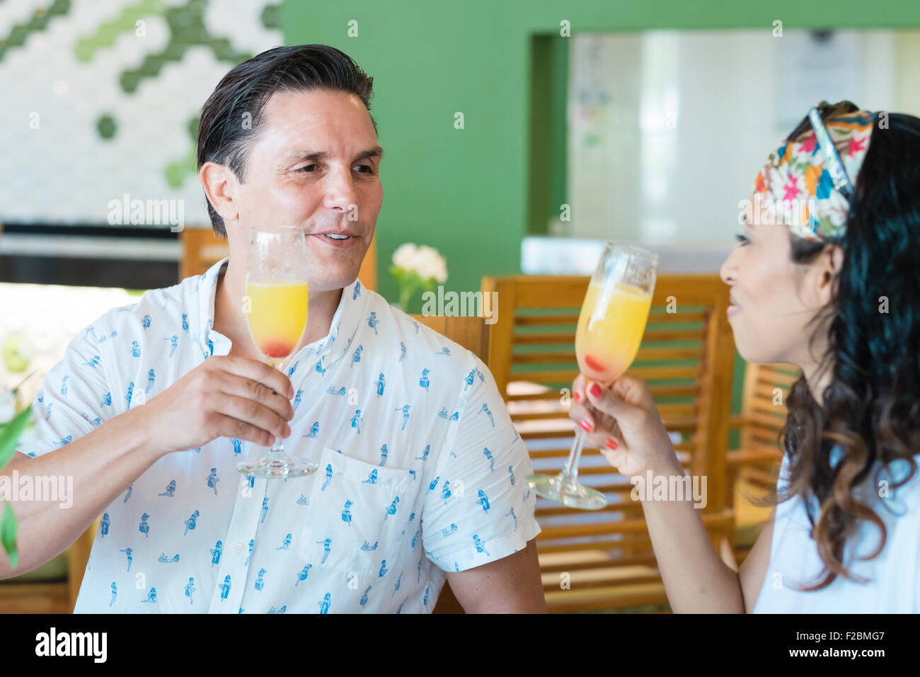 Man and woman drinking orange juice based cocktails Stock Photo - Alamy