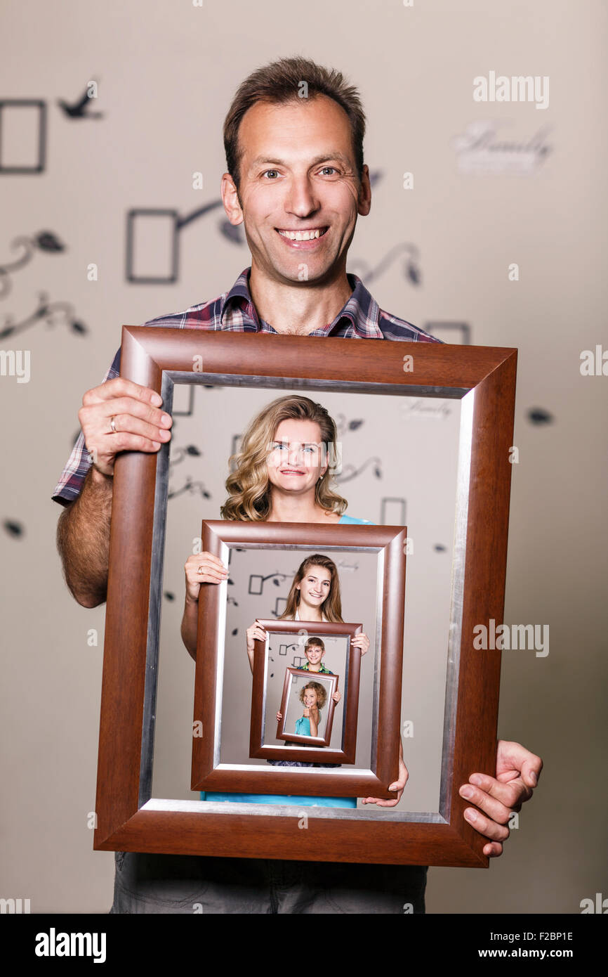 Happy father holding portrait with his family each is located inside ...
