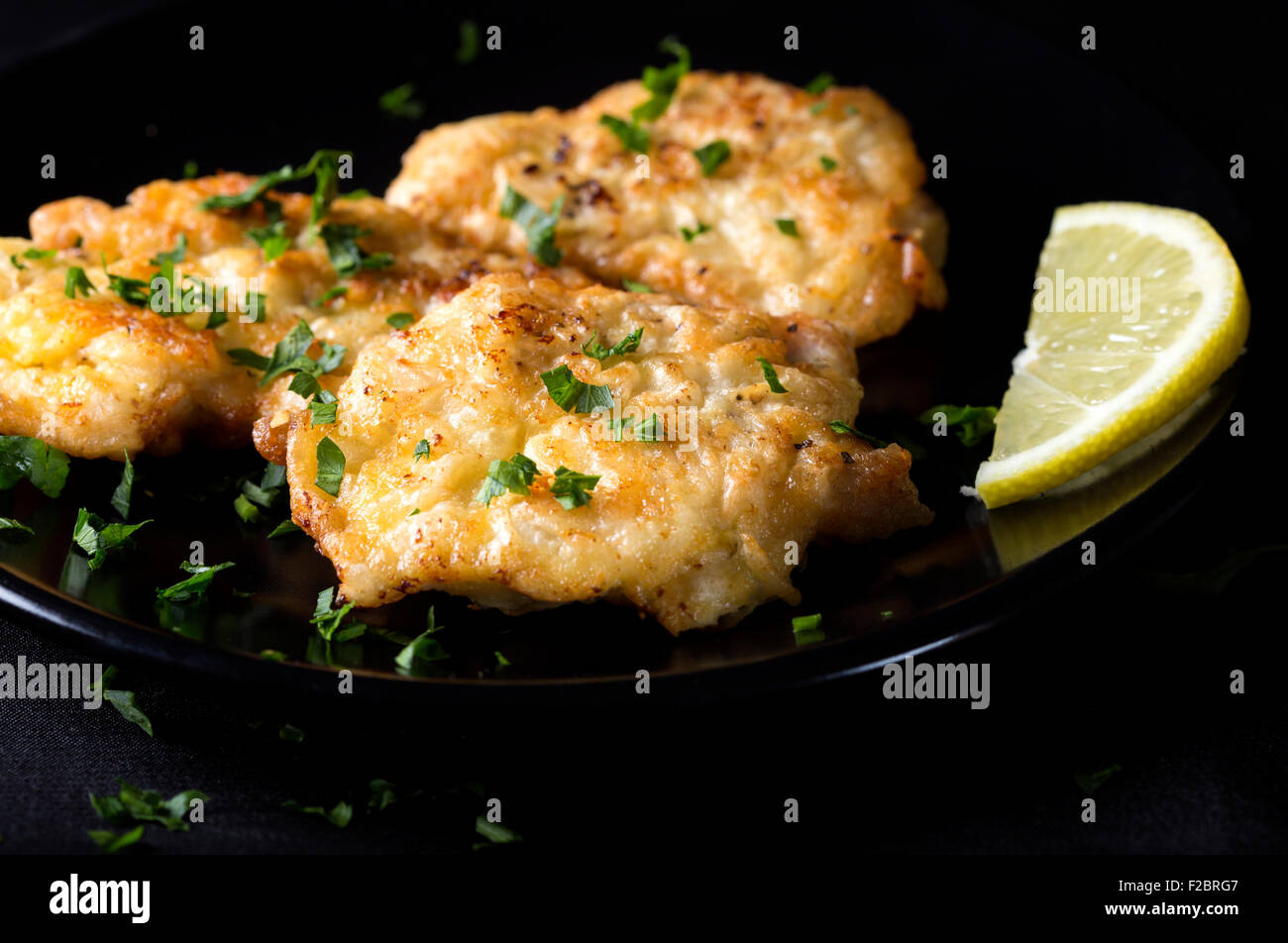 Fried chicken schnitzel with lemon on dark plate Stock Photo - Alamy