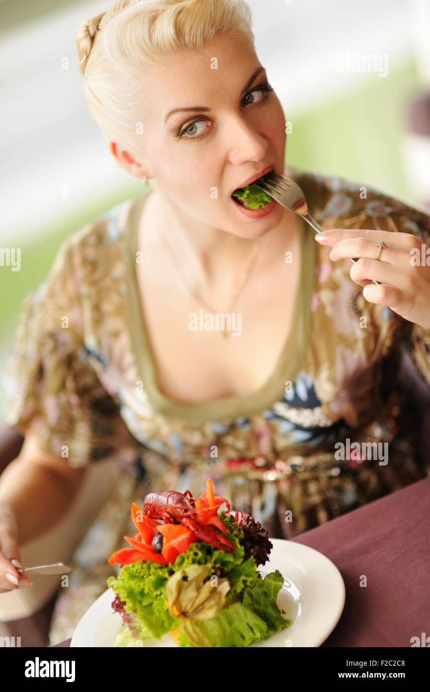 Beautiful woman eating salad in a restaurant Stock Photo - Alamy