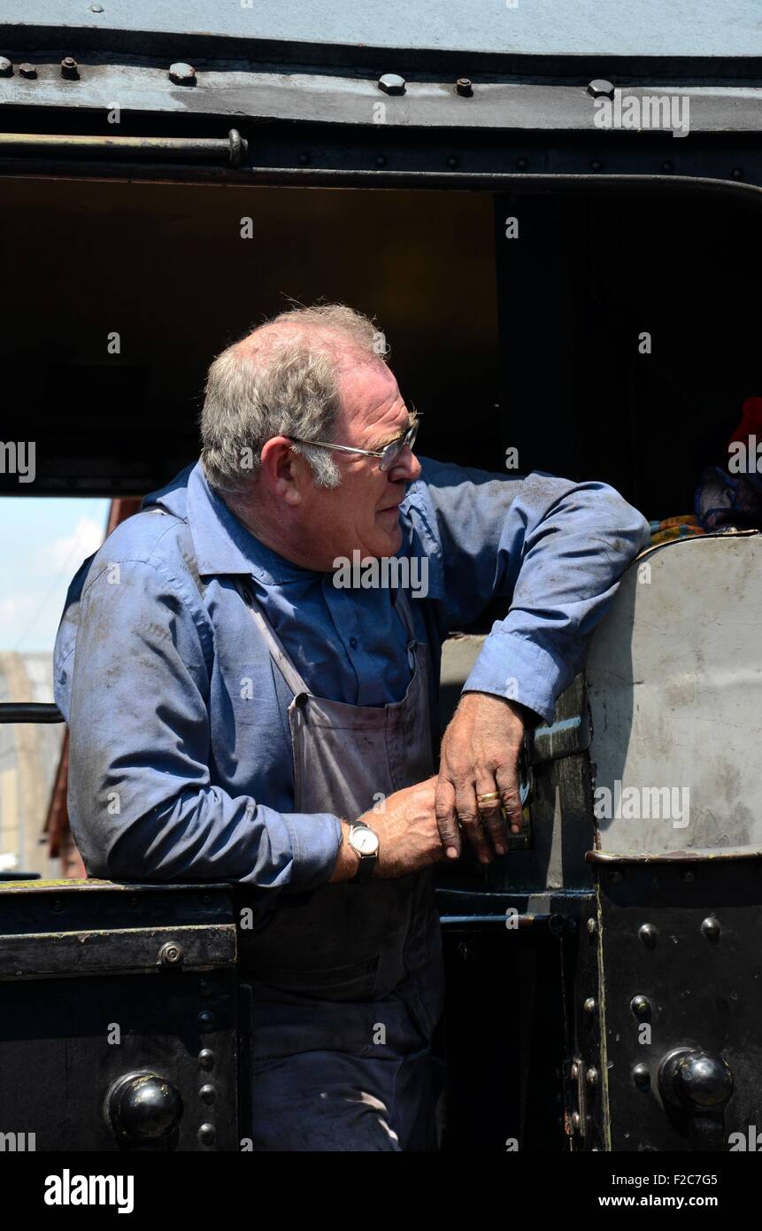 Vintage steam train driver in coal soiled blue overalls in locomotive ...