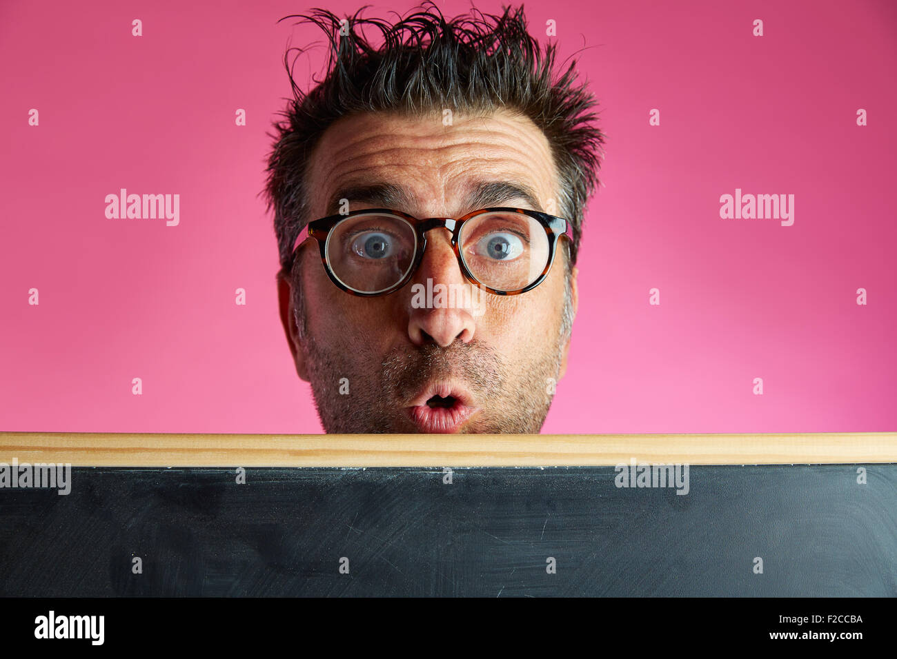 Nerd man crazy behind a blackboard funny surprise gesture in pink ...