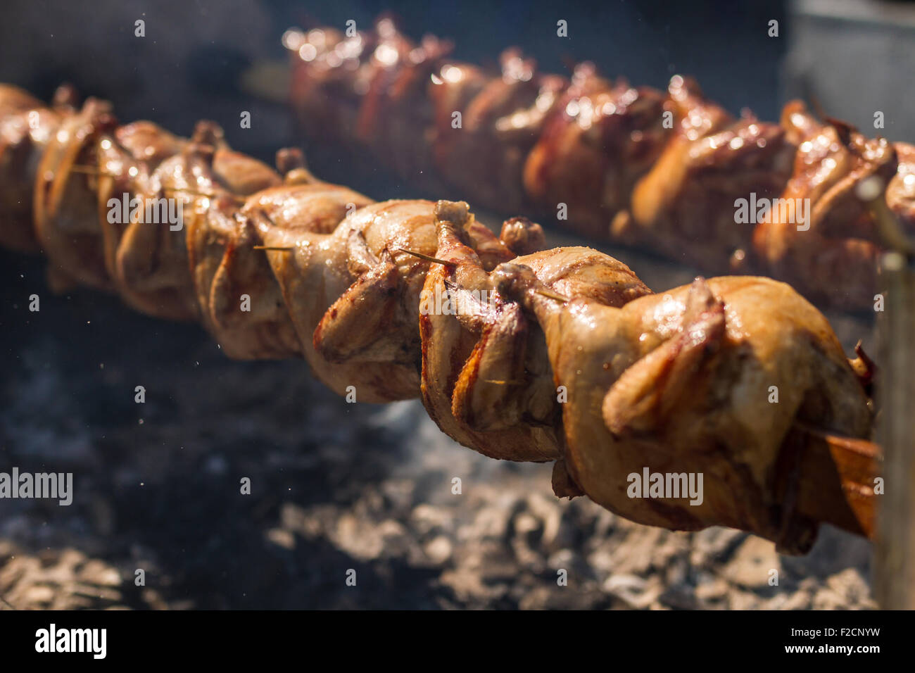 Roast chickens rotating on charcoal grill Stock Photo - Alamy