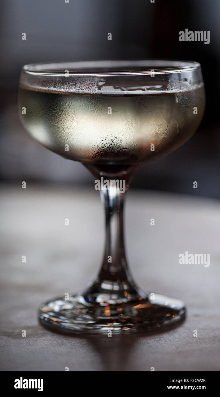Single chilled cocktail with no ice in stemmed glass in dark interior ...