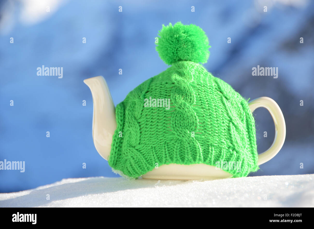 Tea pot in the knitted cap on the snow Stock Photo - Alamy
