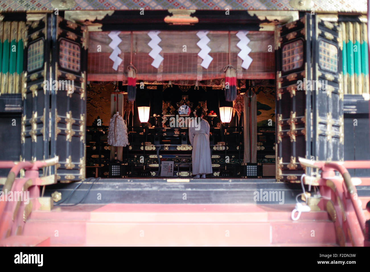Priestess at altar in shrine doors and red steps Stock Photo - Alamy
