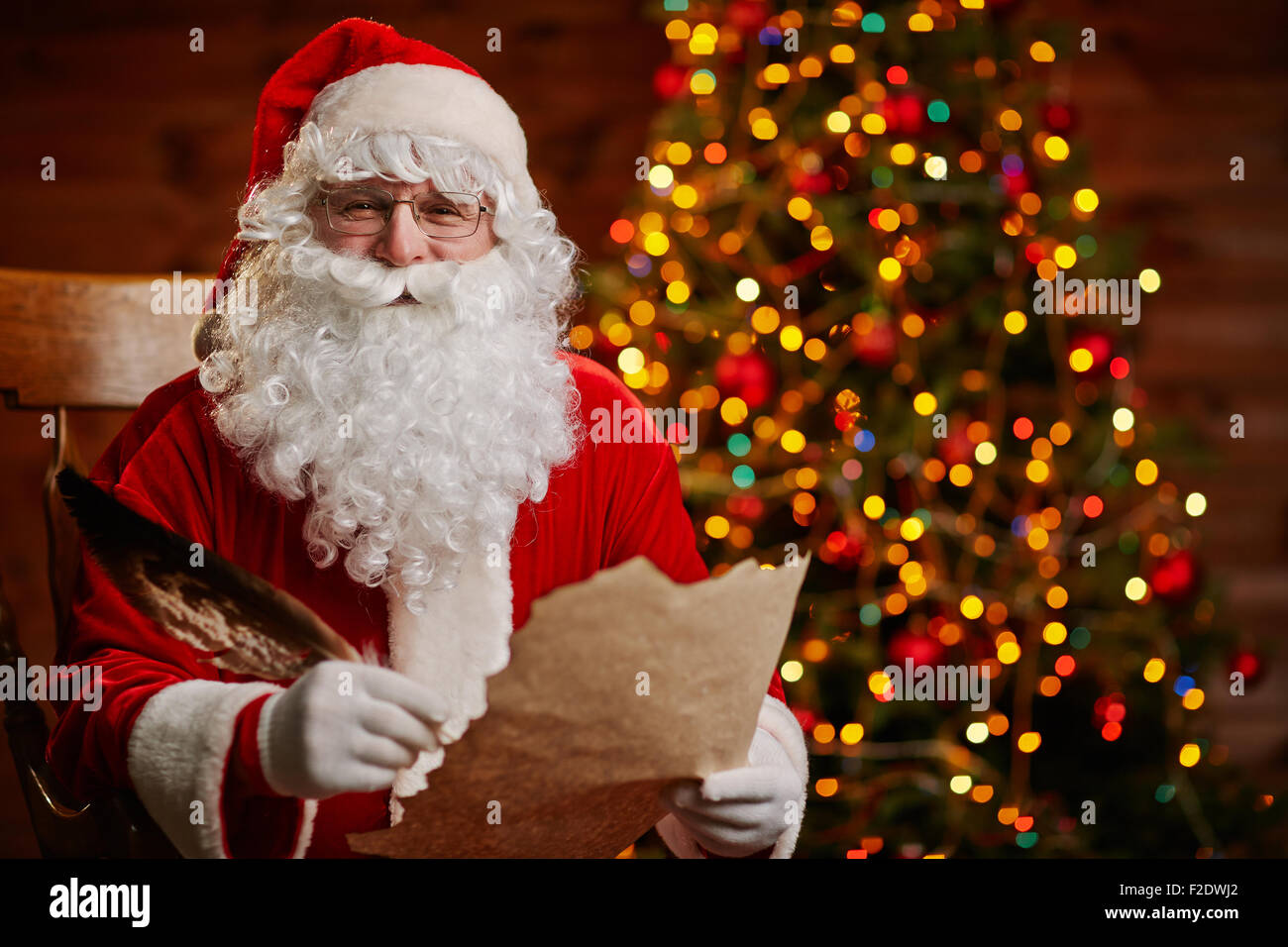 Senior man in costume of Santa Claus holding feather and Christmas ...