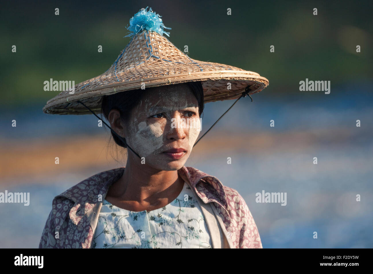 Local woman with straw hat and Thanaka paste on her face, portrait ...
