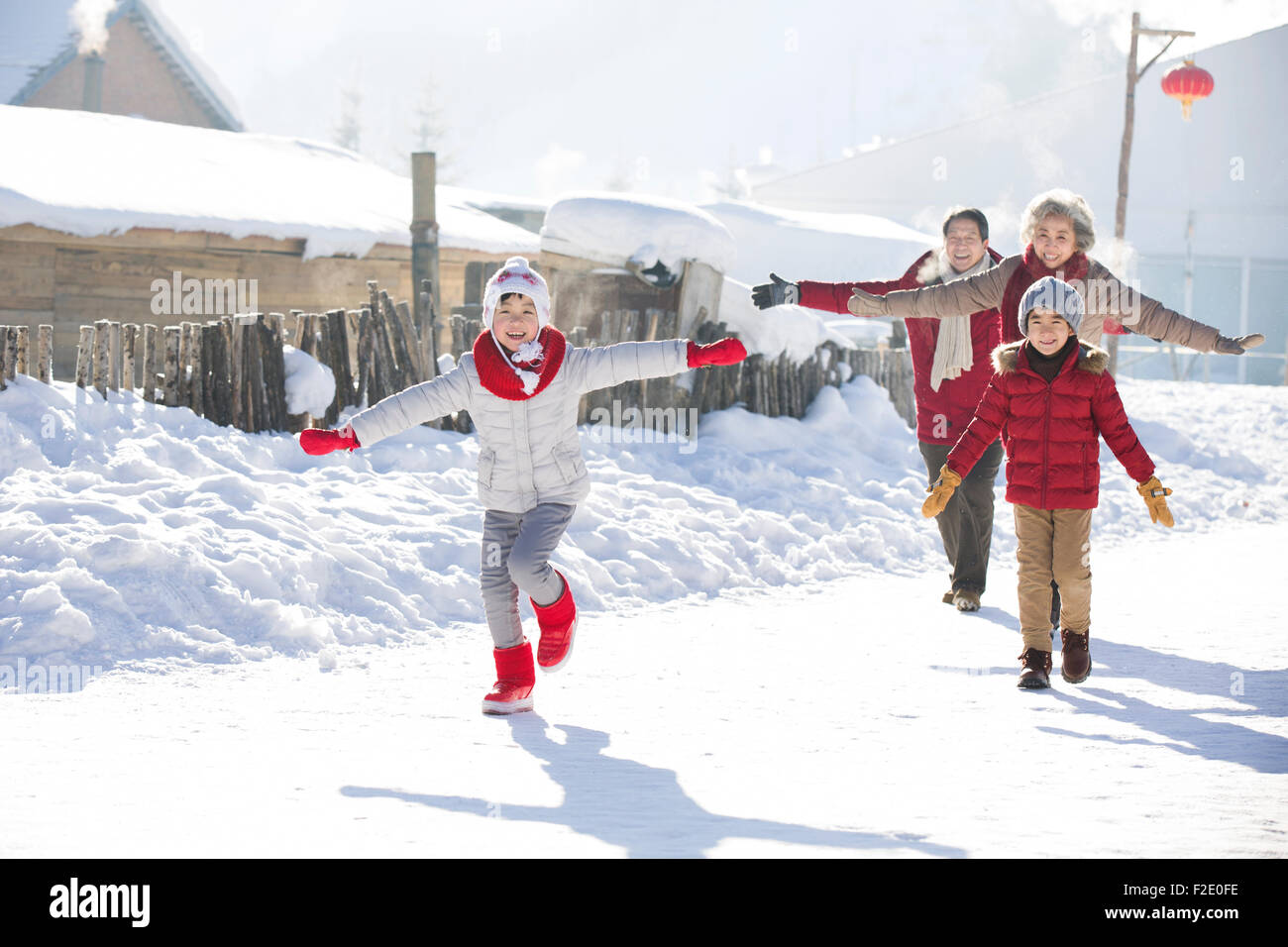 Happy family running in the snow Stock Photo - Alamy