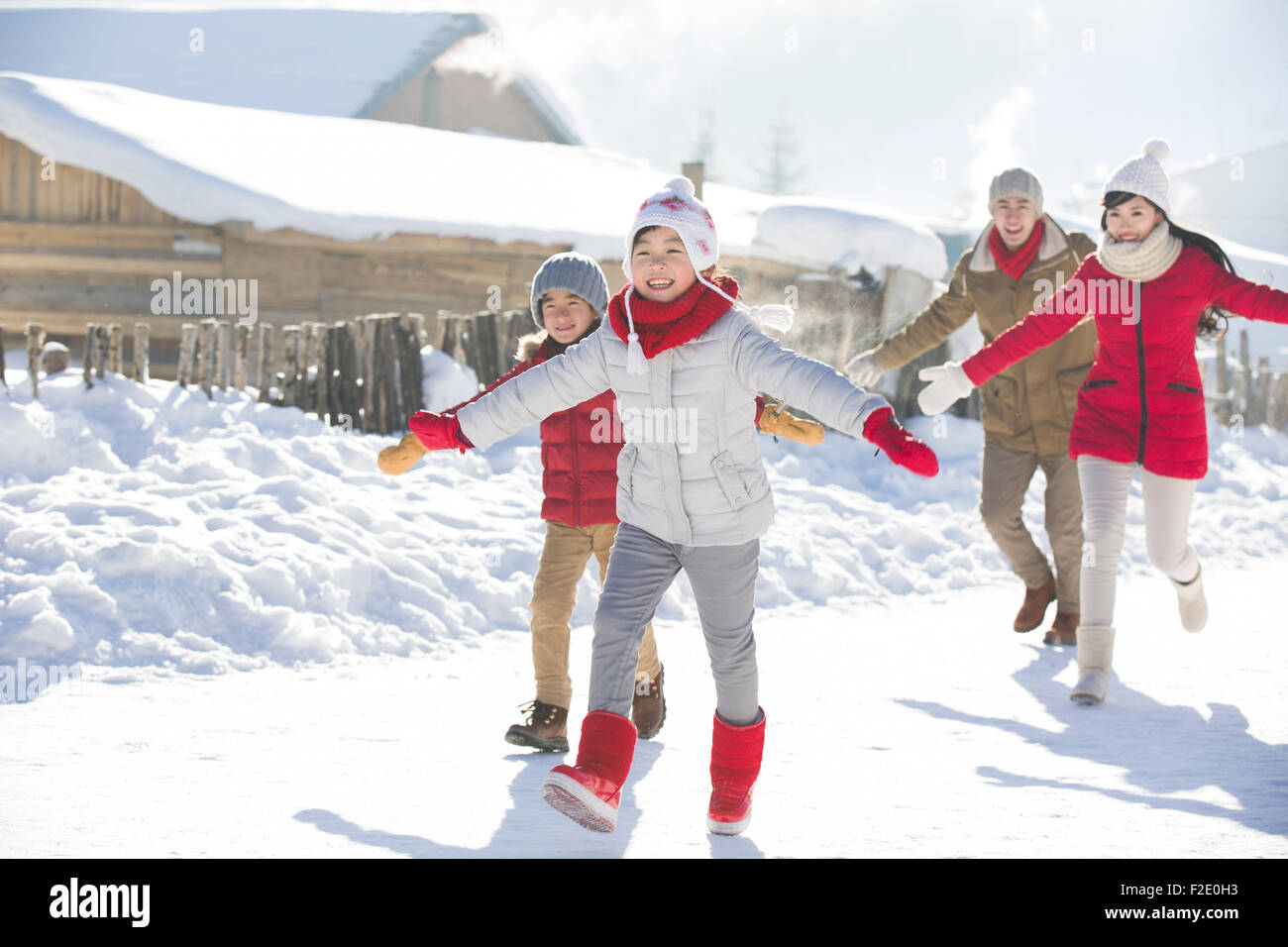 Happy family running in the snow Stock Photo - Alamy