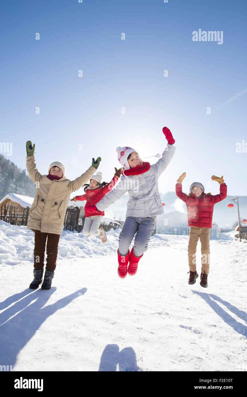 Happy children jumping in the snow Stock Photo - Alamy