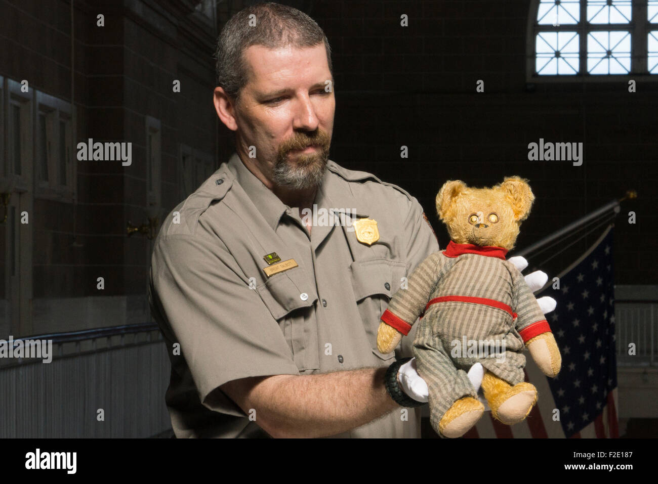 An exhibit specialist at Ellis Island holding a teddy bear that a child ...