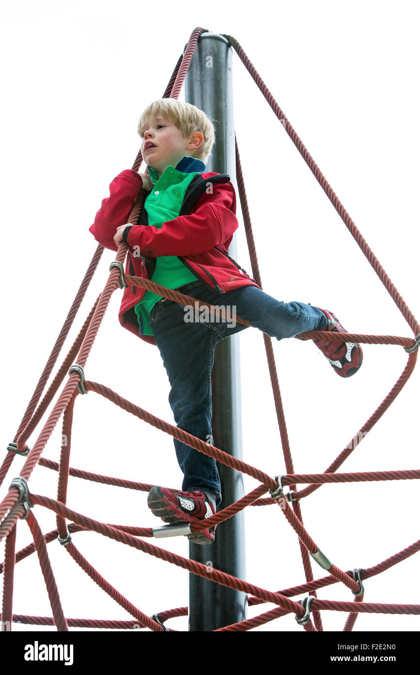 blond boy climbing on ropes on playground on a rainy day Stock Photo ...