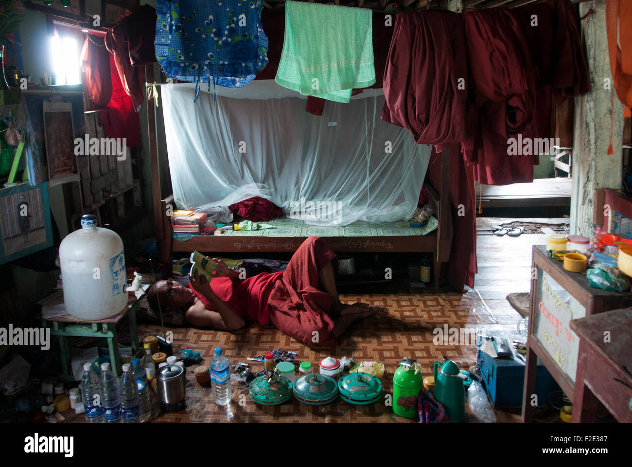 A Buddhist monk reading a book in his room at a monastery in Kyauktan ...