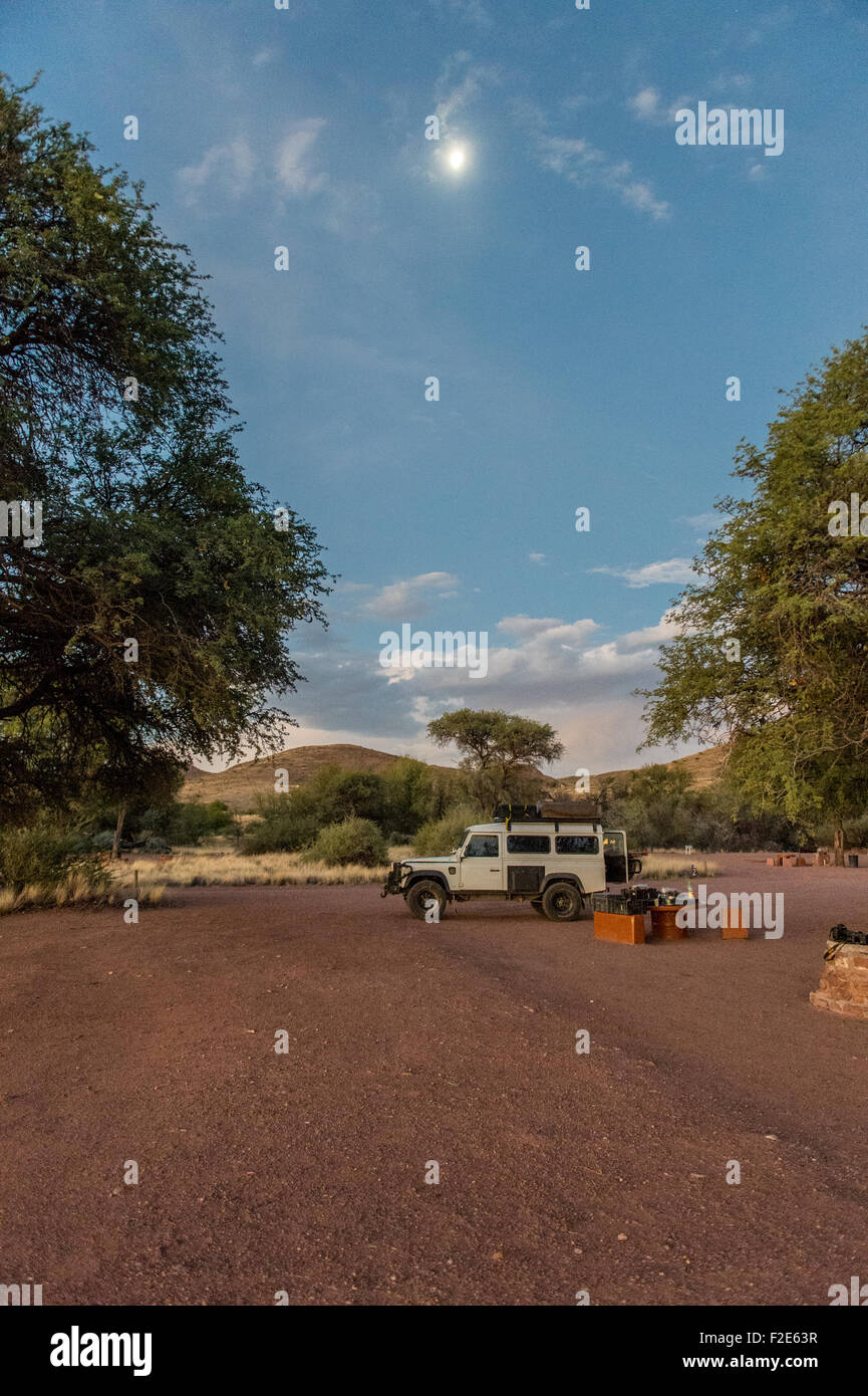 Land Rover Defender 110 parked at a designated campground, setting up ...