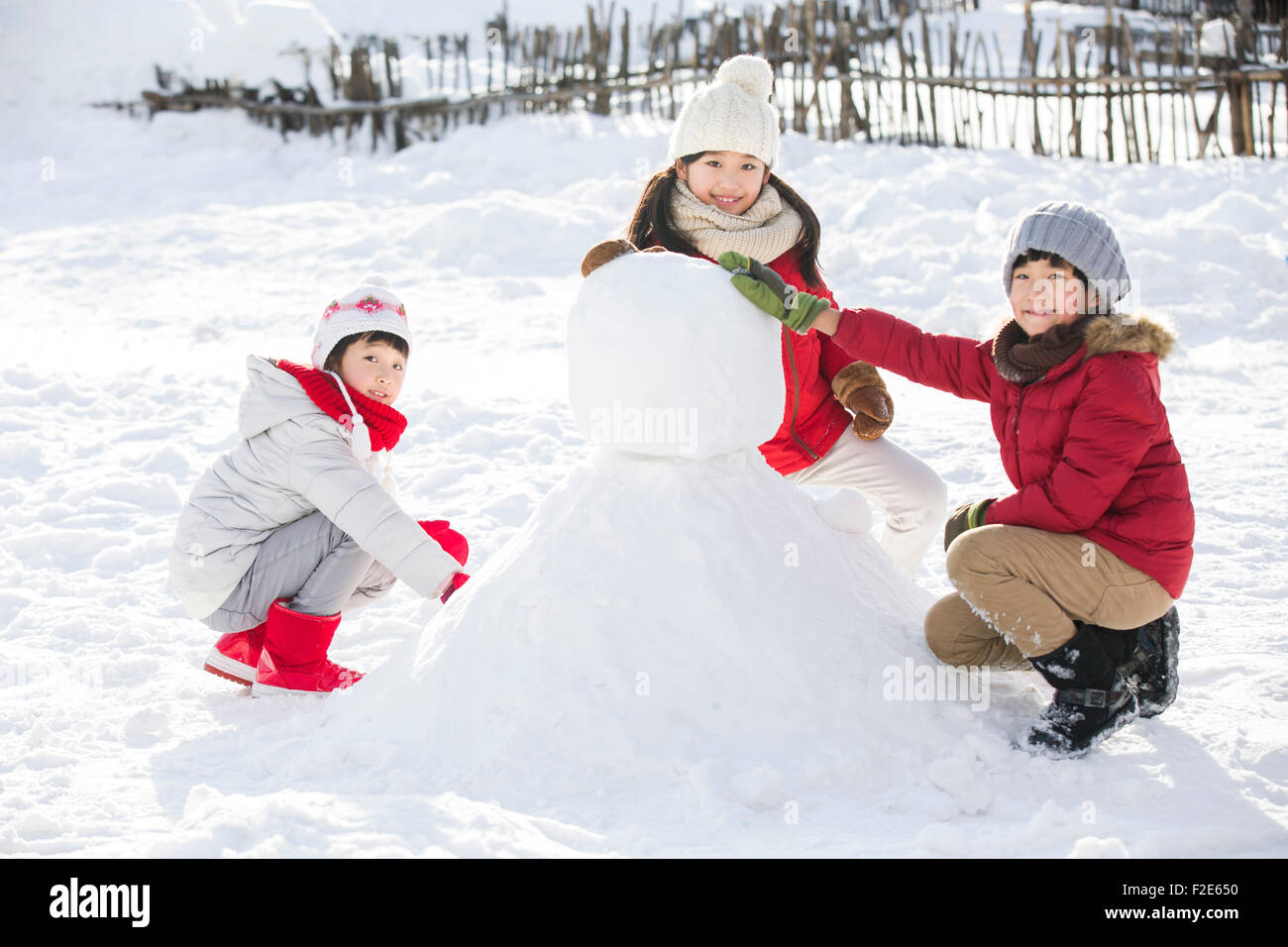 Happy children making snowman together Stock Photo - Alamy