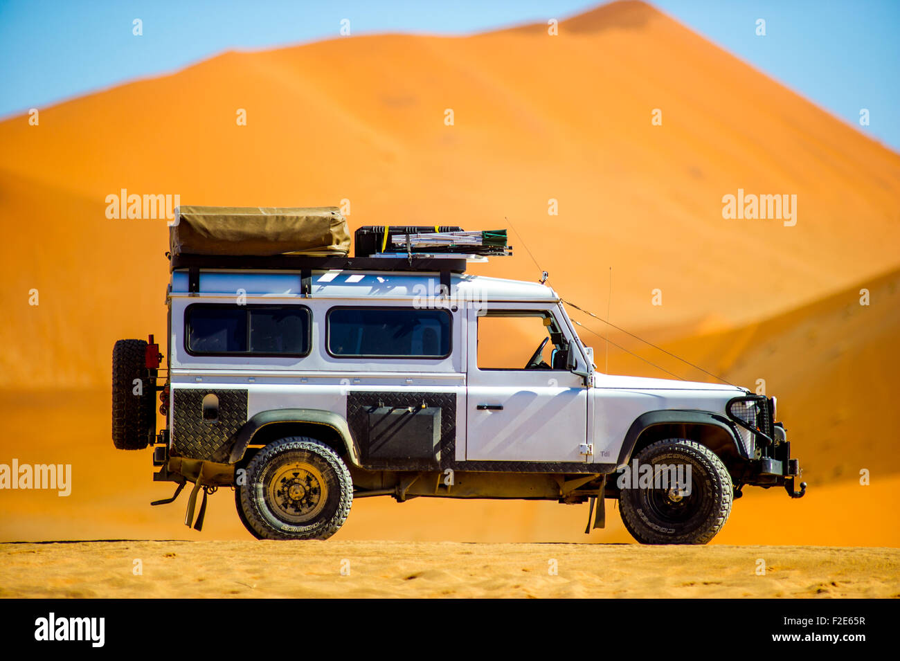 Land Rover Defender 110 parked in the desert with dunes in the distance ...
