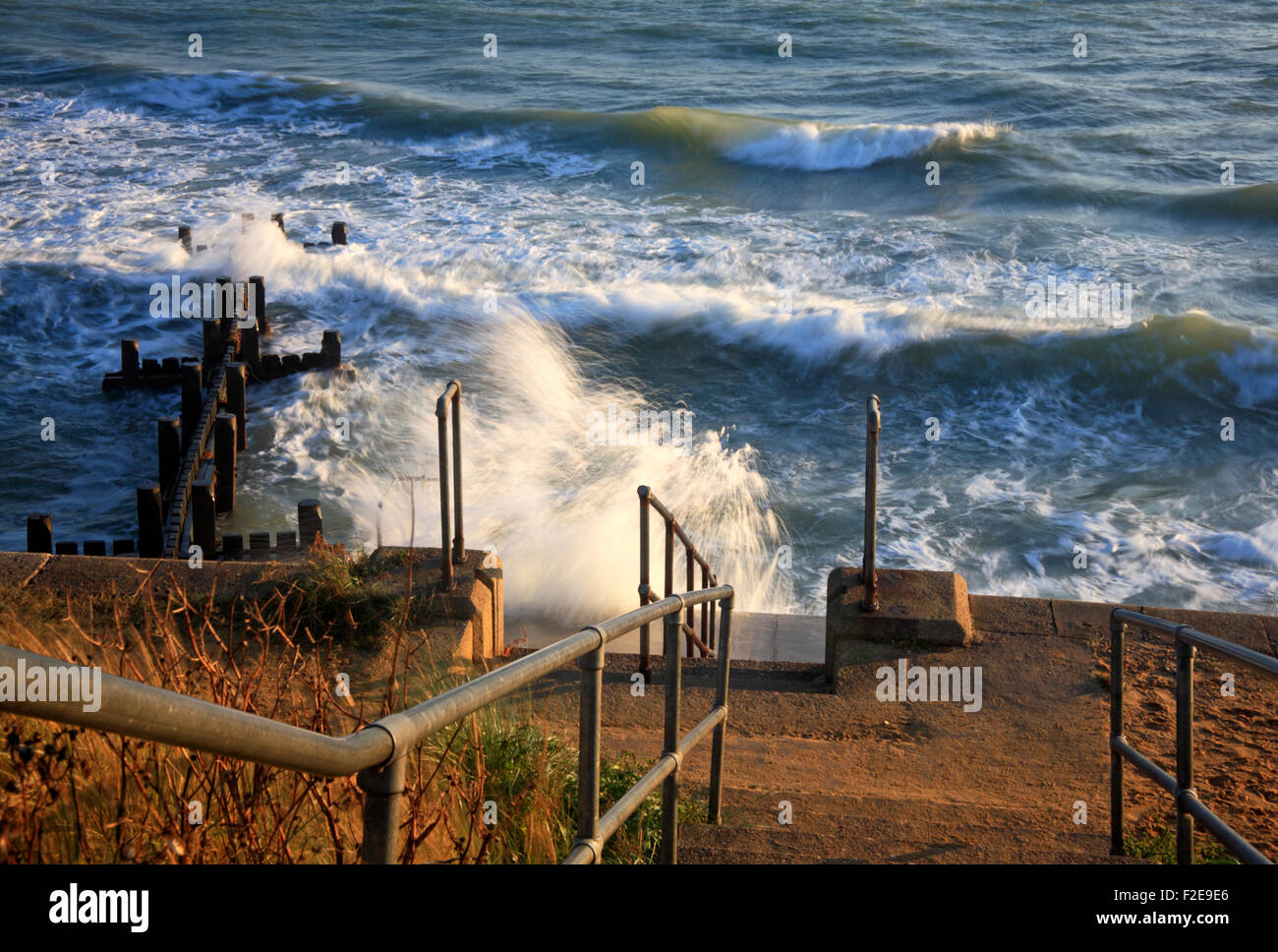 A beach access with high tide buffeting the sea wall on the east coast ...