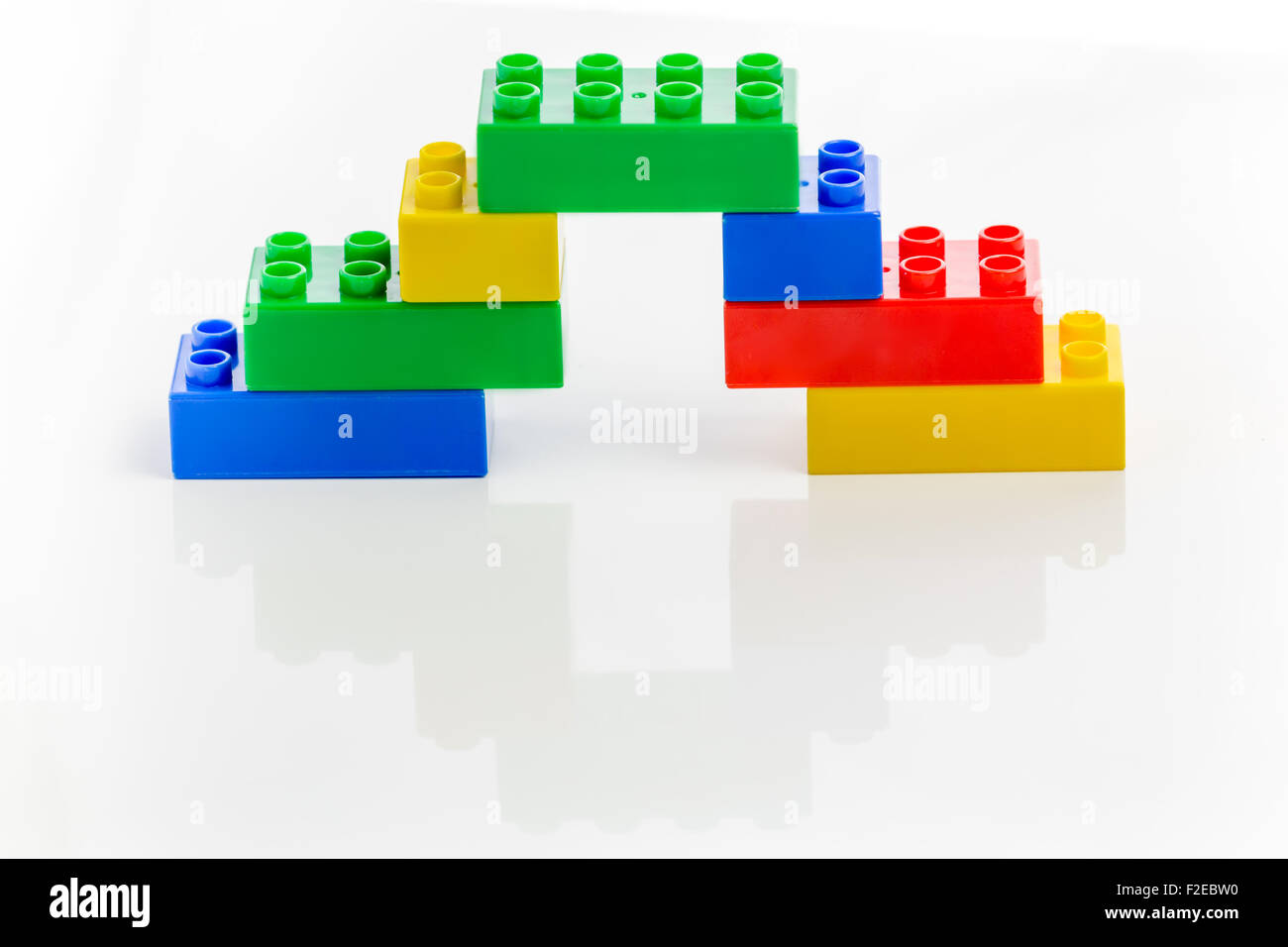Colorful plastic building bricks forming bridge on white background ...
