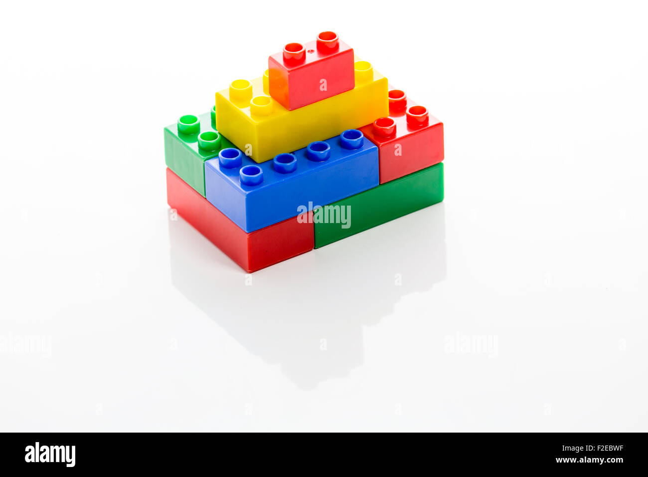Colorful plastic building bricks forming building on white background ...