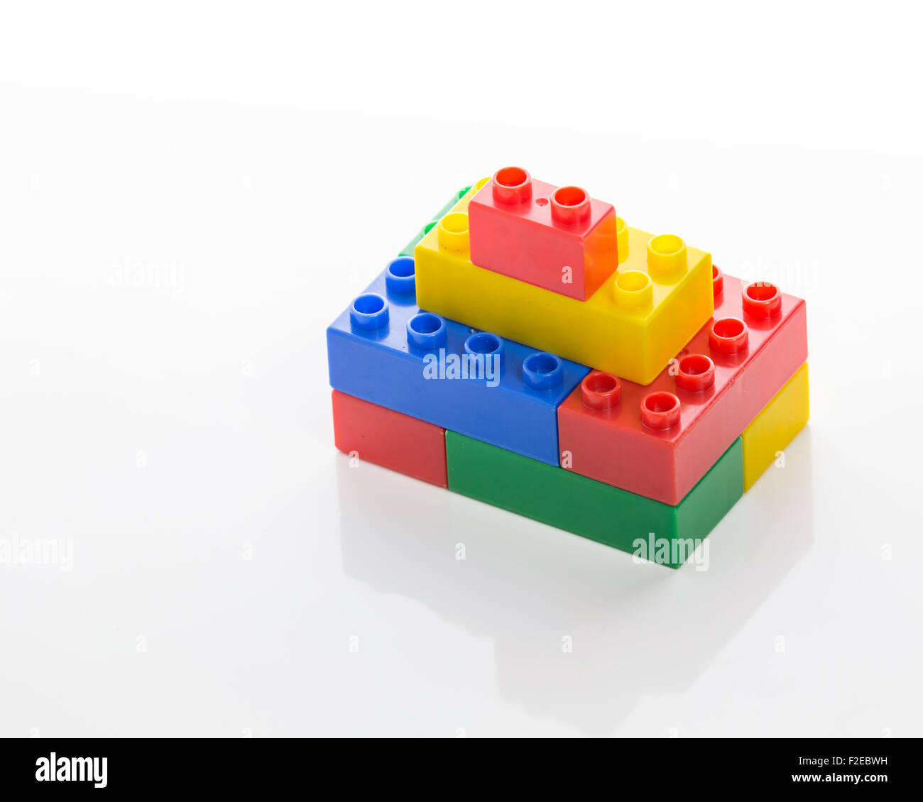 Colorful plastic building bricks forming building on white background ...