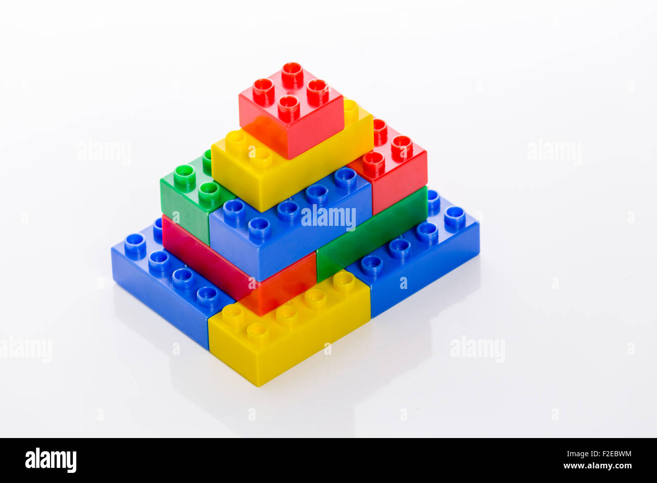 Colorful plastic building bricks forming building on white background ...