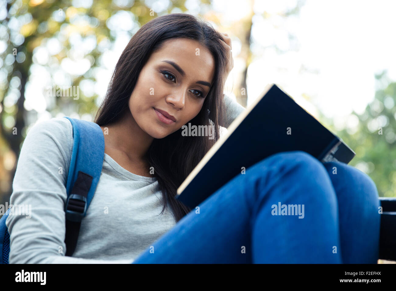 Portrait of a happy cute girl reading book outdoors Stock Photo - Alamy