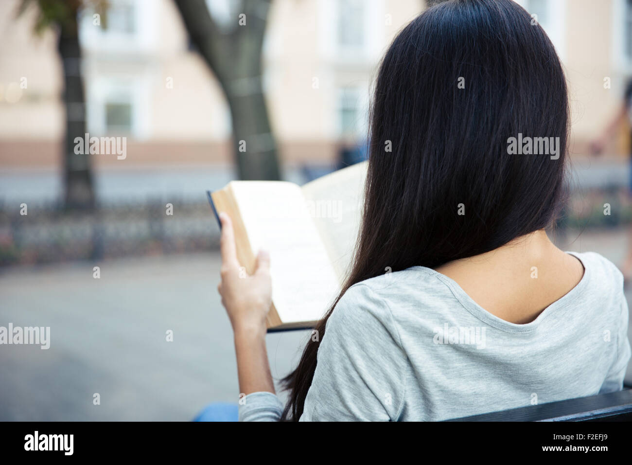 Back view portrait of a woman reading book outdoors Stock Photo - Alamy
