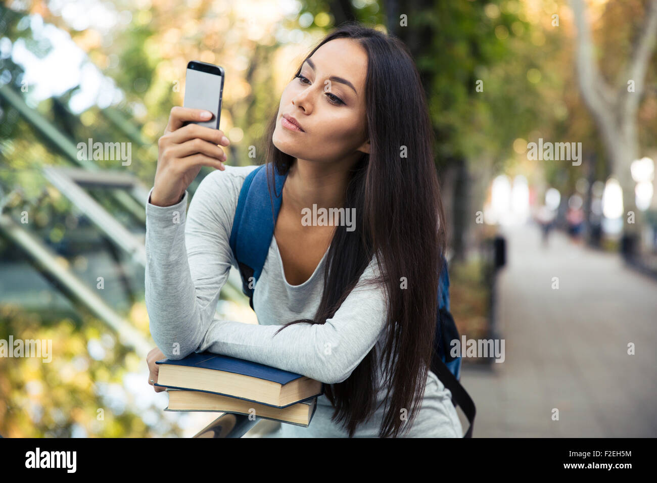 Portrait of a beautiful female student using smartphone outdoors Stock ...