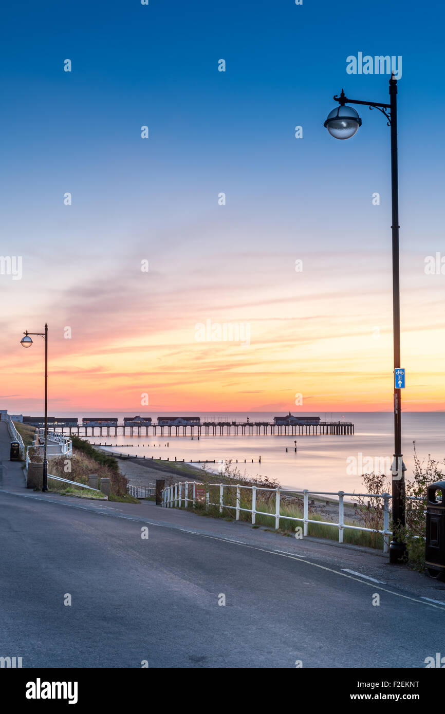 The street lights dim as the sun rises behind the pier in the Suffolk ...