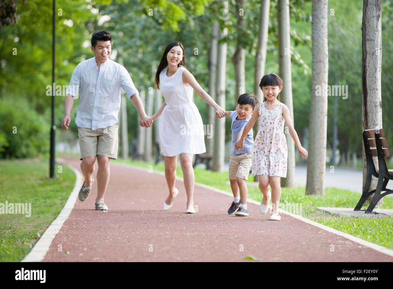 Happy young family running in park Stock Photo - Alamy