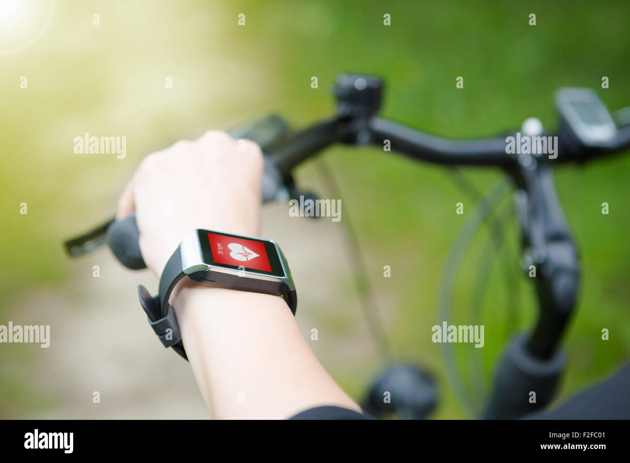 Woman riding a bike with a smartwatch heart rate monitor. Smart watch ...