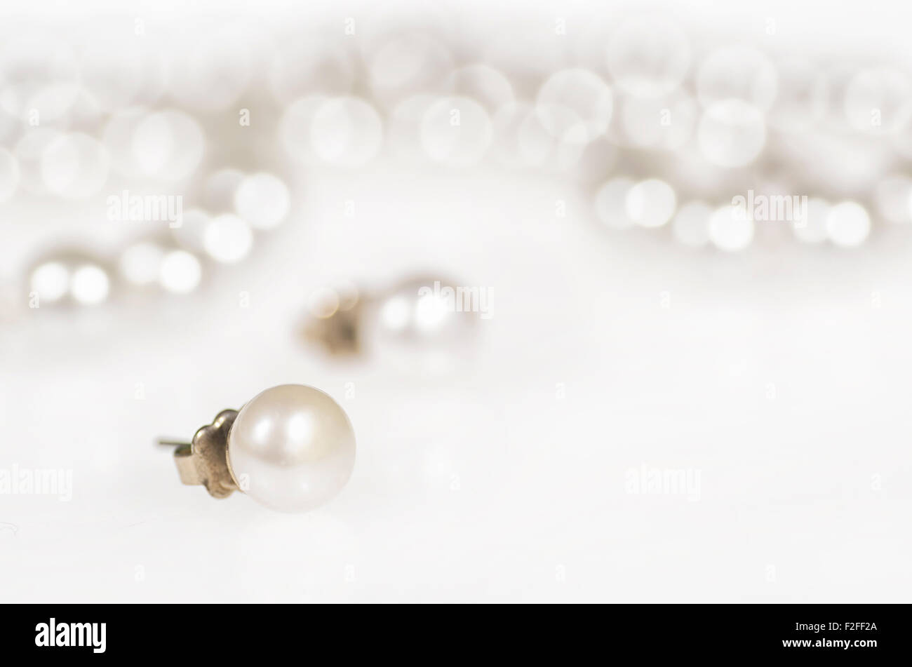 Pearl earring on a blurry background Stock Photo - Alamy