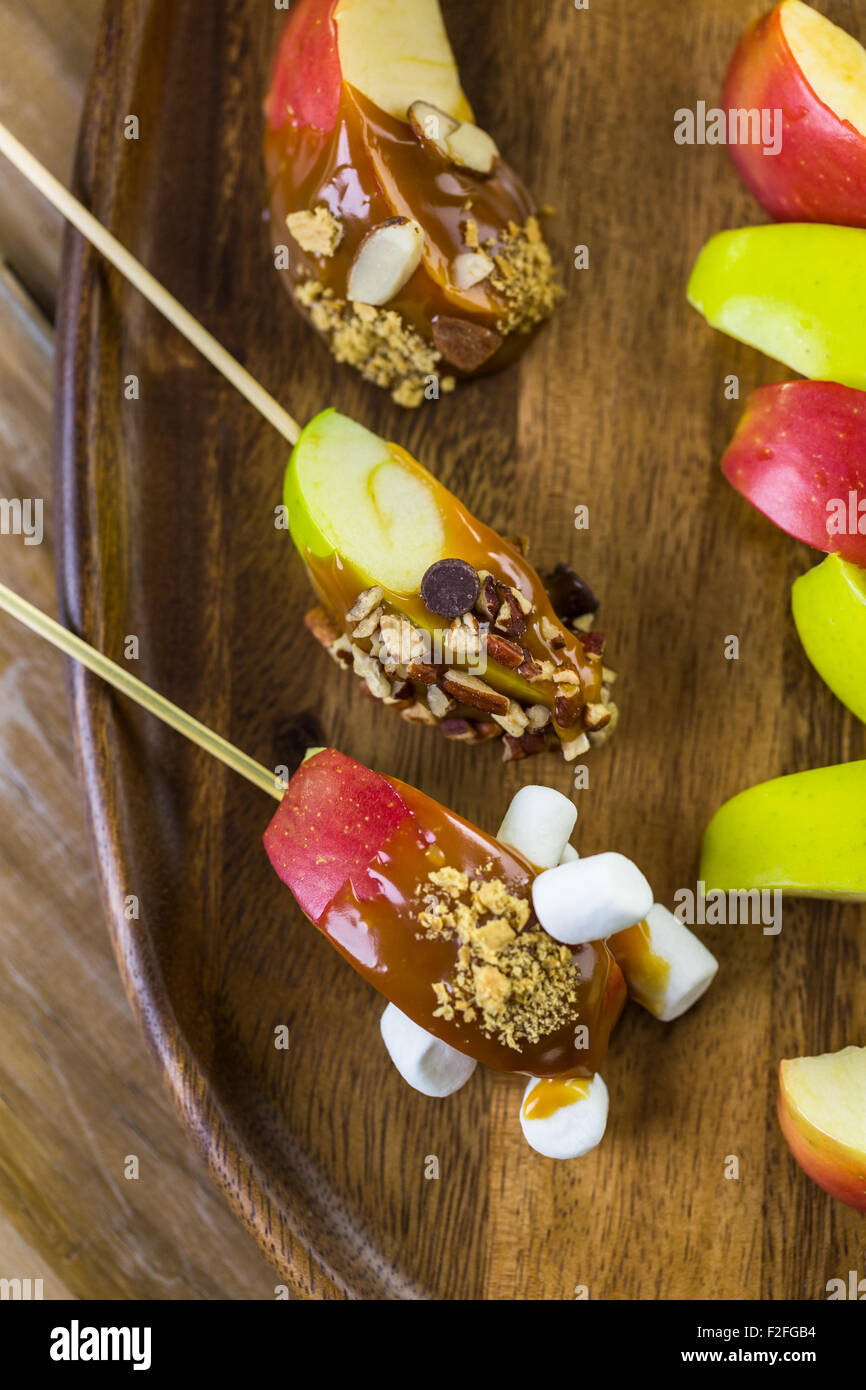 Apple slices dipped in caramel and covered with different toppings ...