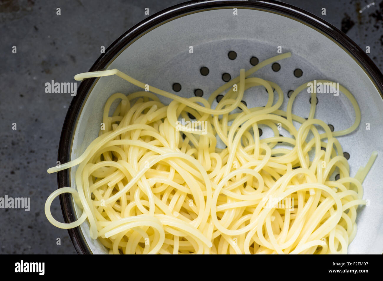 Spaghetti cooked and put in an enamel colander top view Stock Photo - Alamy