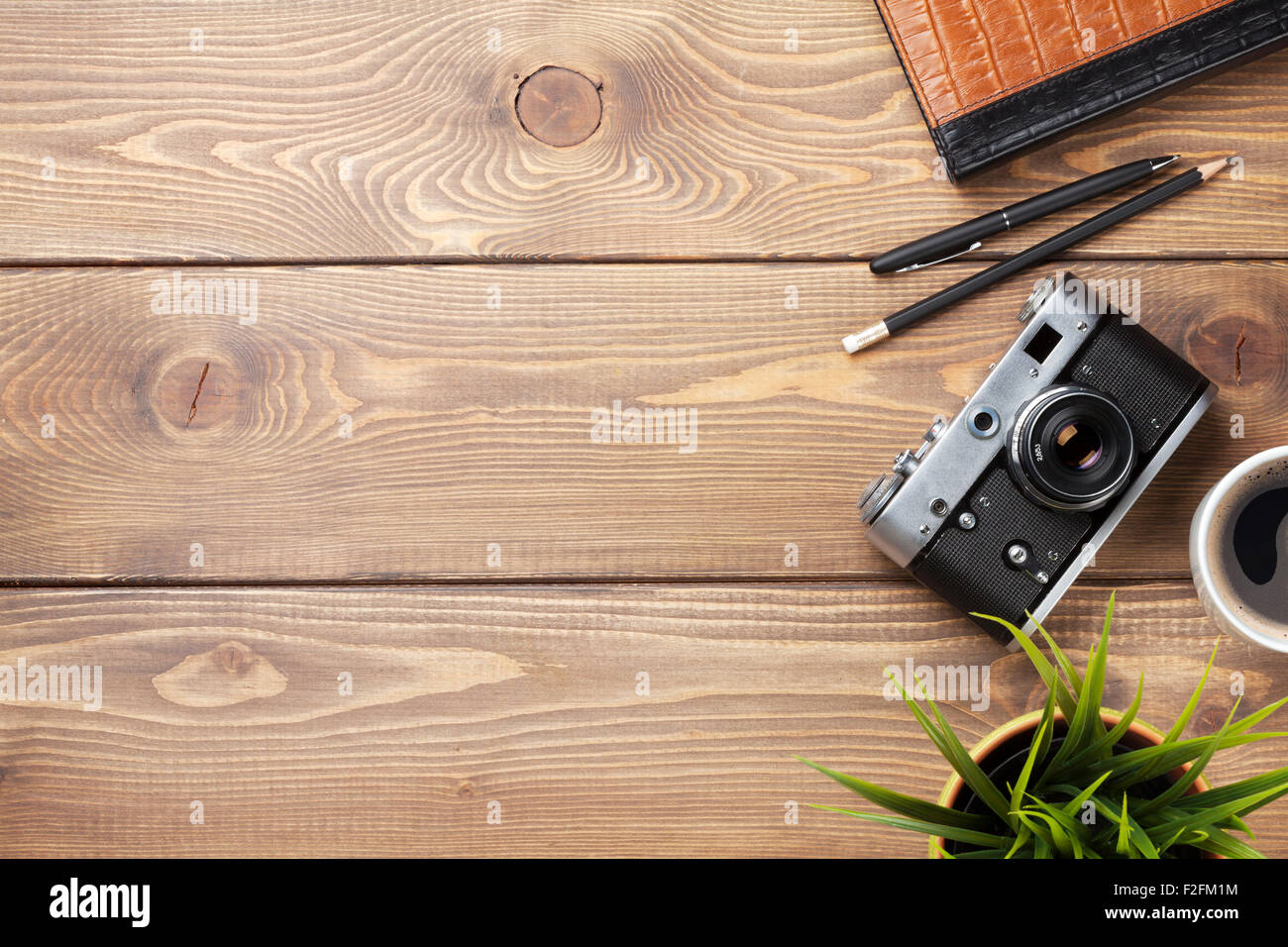 Camera and supplies on office wooden desk table. Top view with copy ...