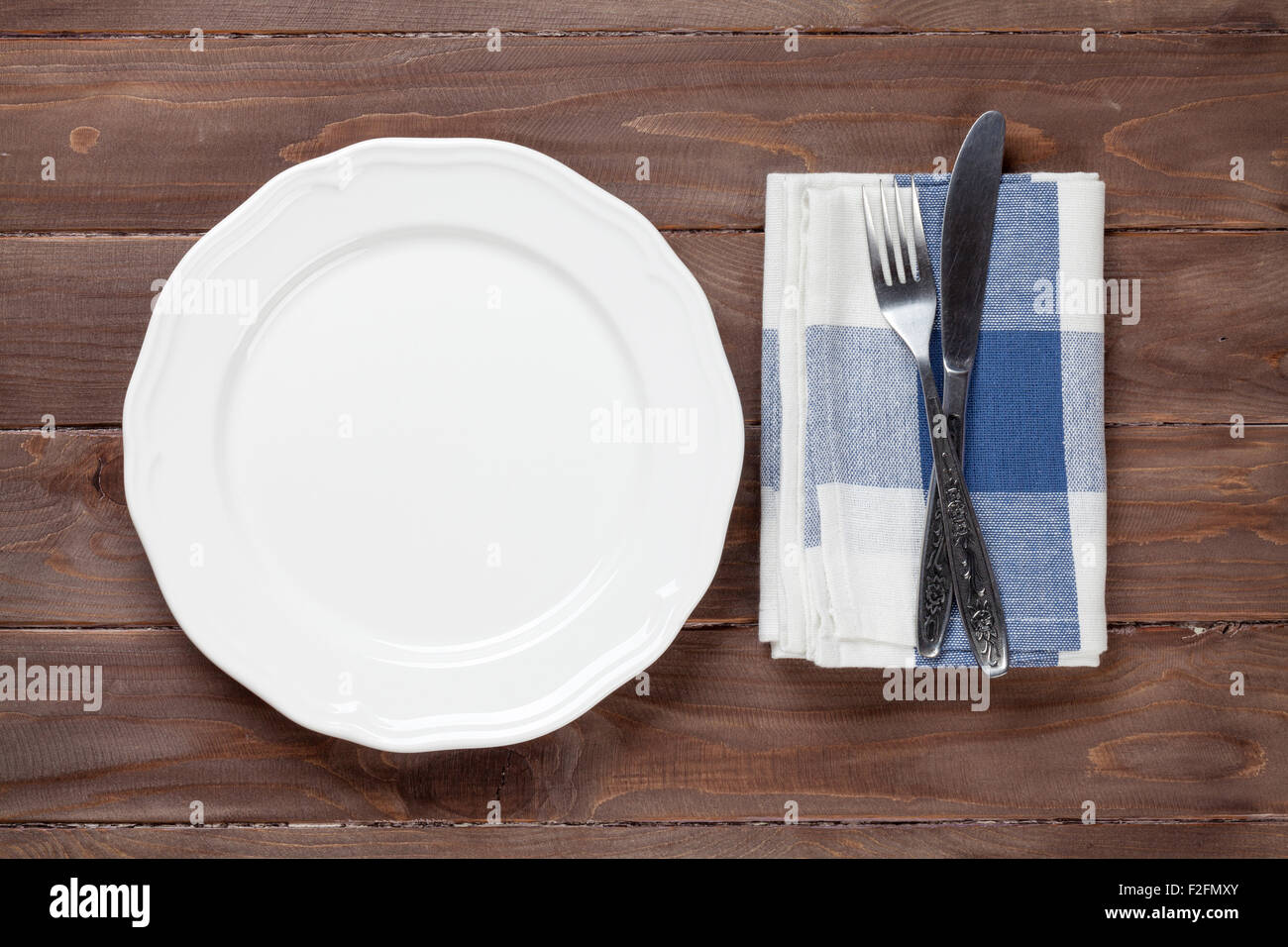 Empty plate and silverware over wooden table background. View from ...