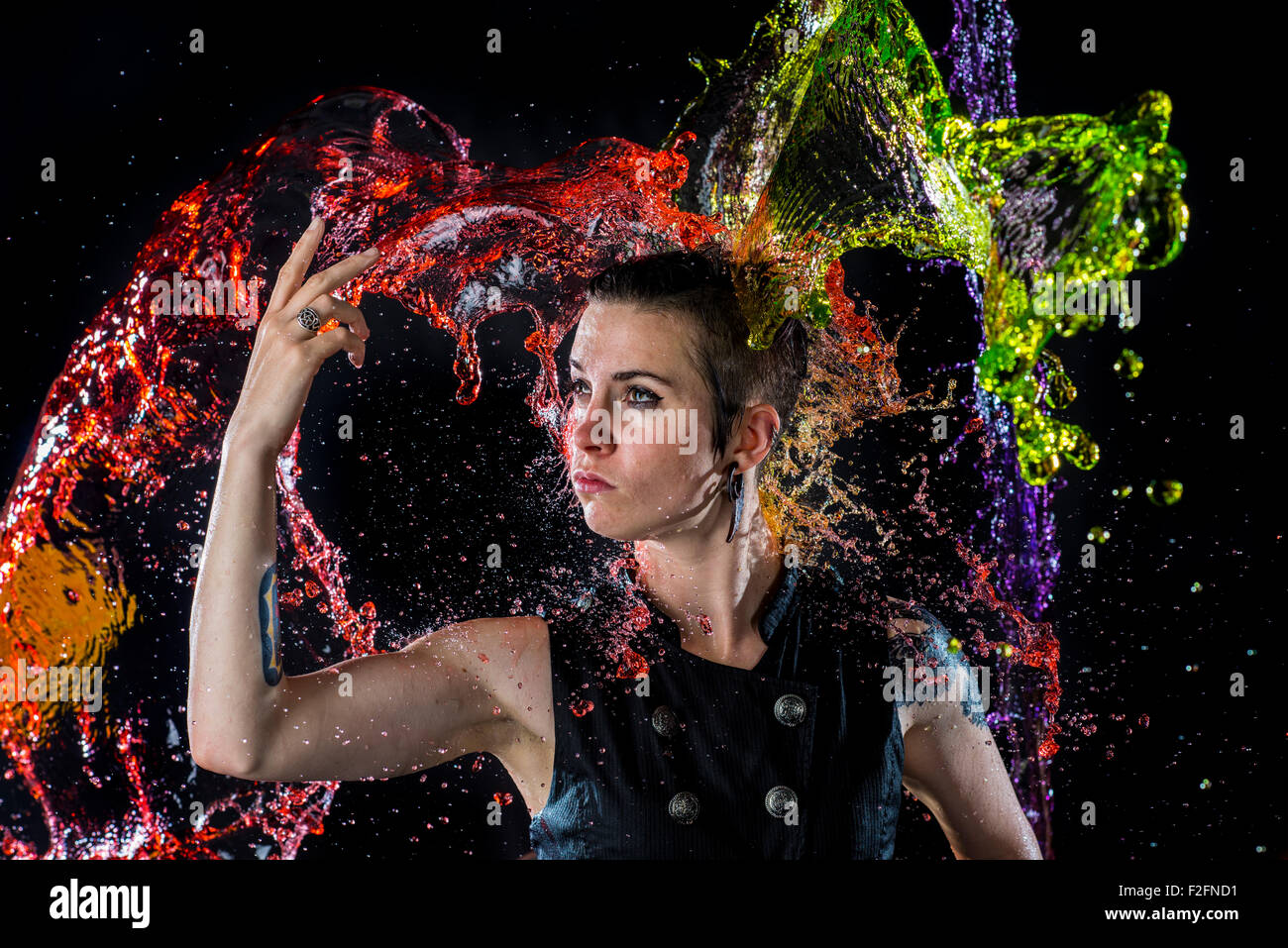 Modern Woman Being Splashed with Colorful Water Stock Photo - Alamy